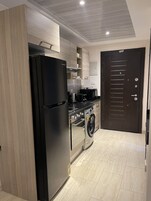 Uma cozinha moderna com geladeira preta, máquina de lavar e micro-ondas.