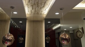 Teto com painel de madeira, iluminação embutida e lustres esféricos pendentes.
