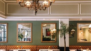 Uma sala de jantar com várias mesas, cadeiras e um lustre grande.
