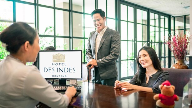 Uma receção com um monitor de computador a exibir 'HOTEL DES INDES MENTENG'.