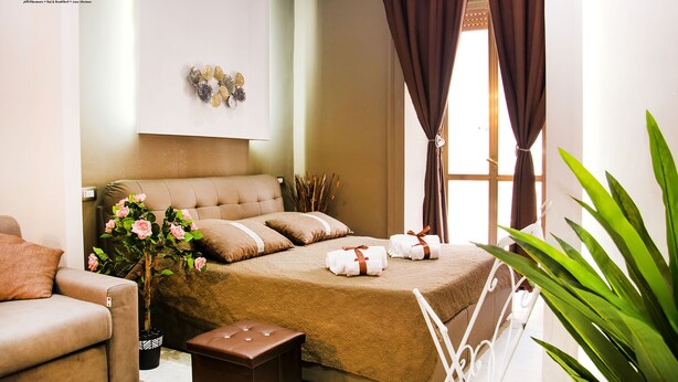 Quarto com cama grande, um sofá, uma mesinha e um vaso de planta.