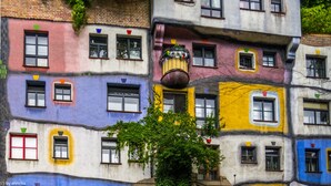Um edifício com várias andares, fachadas coloridas e várias janelas.