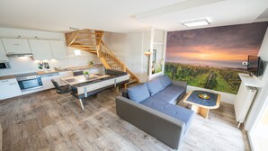 Um apartamento moderno com cozinha, área de refeições e sala de estar com uma grande janela com vista para um vinhedo.