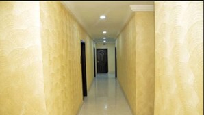 Um corredor com paredes estampadas e chão em azulejos, que leva a uma porta no final.