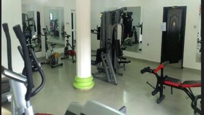 Academia com diversos equipamentos de exercício, um espelho e uma porta.