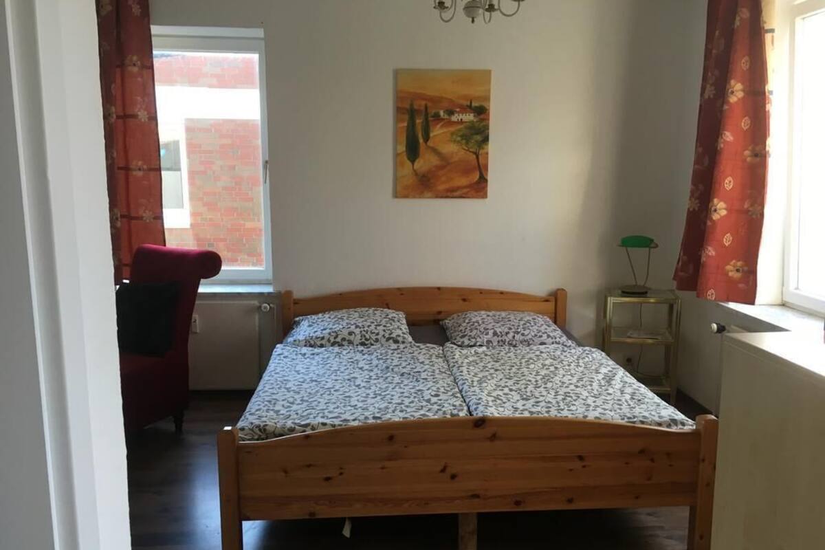 Quarto com cama de madeira, um quadro na parede e janela com cortinas.