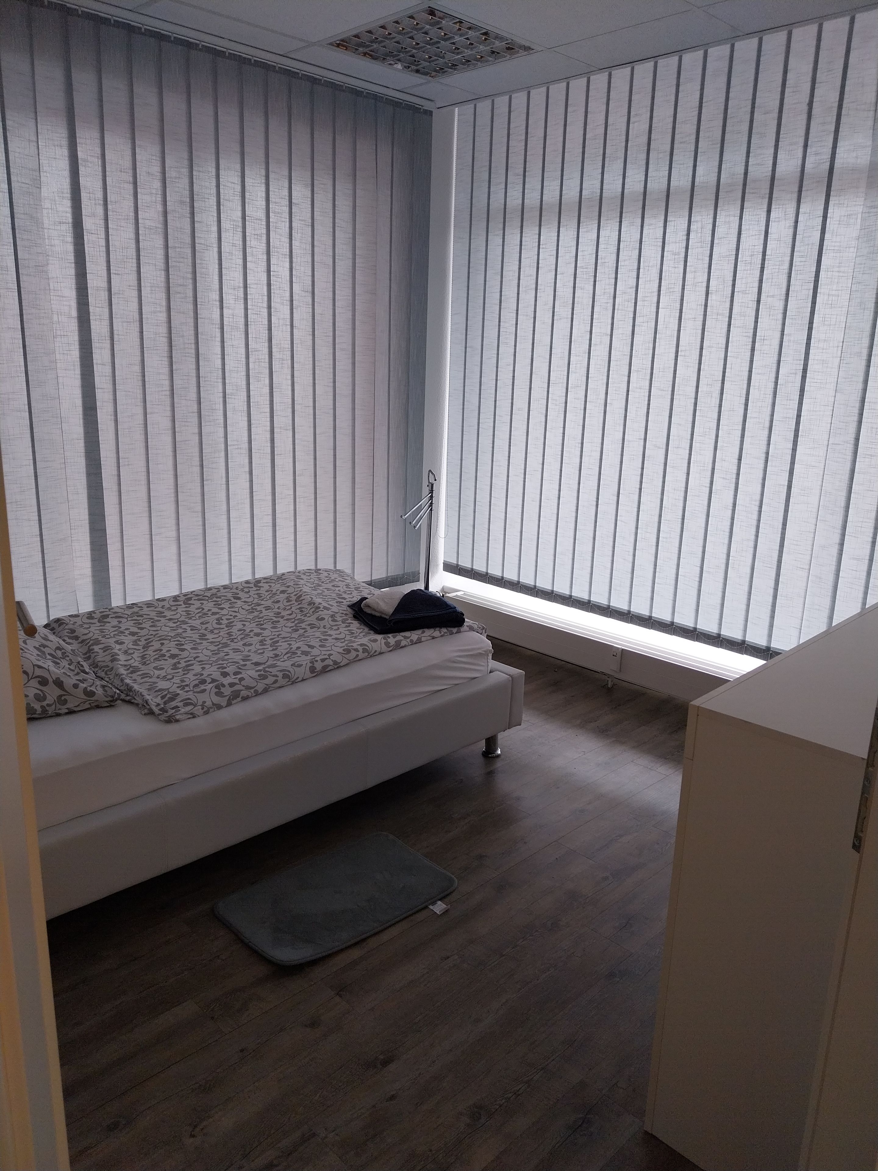 Quarto com cama, janela e radiador.