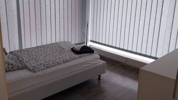 Quarto com cama, janela e radiador.