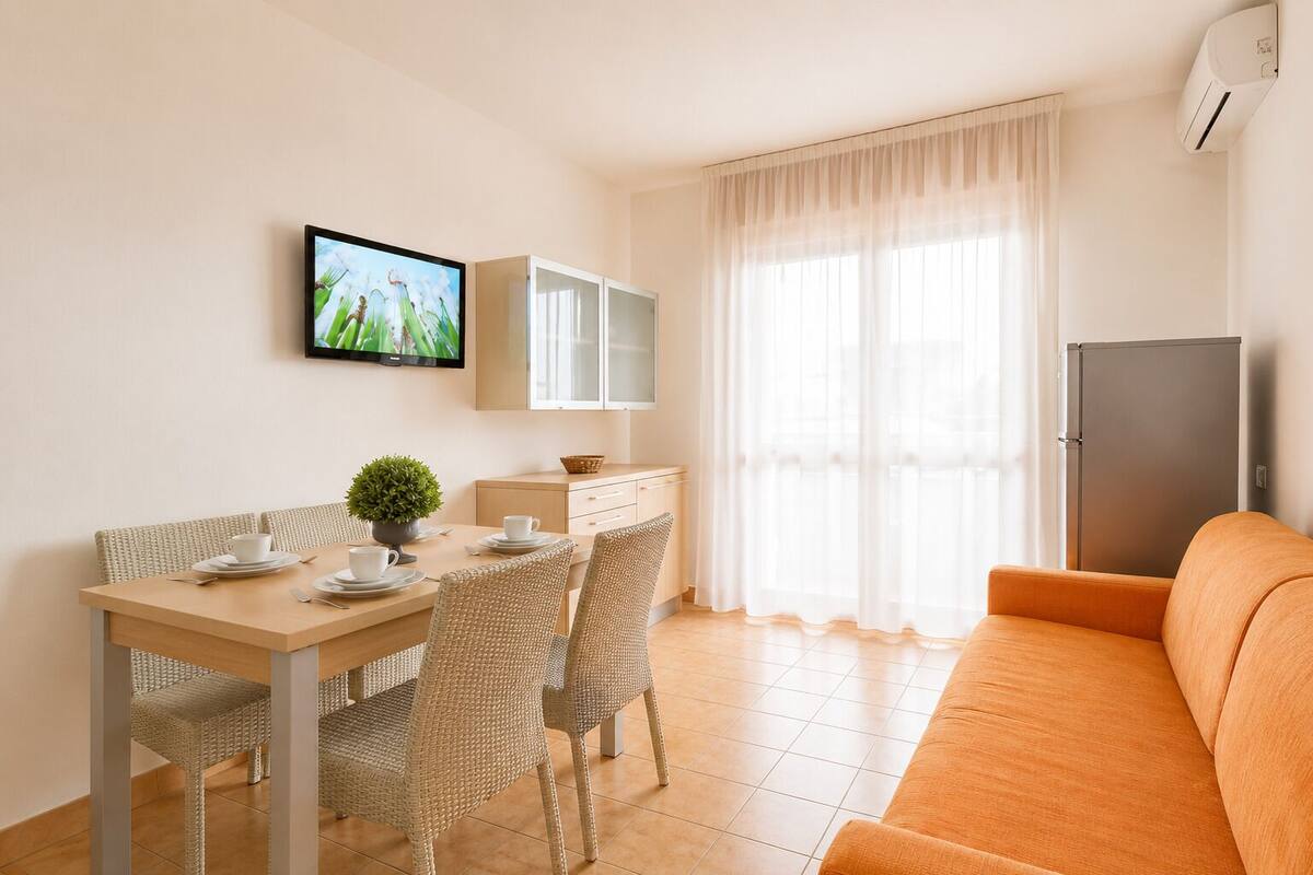 Uma sala de estar moderna com área de jantar, televisão na parede, geladeira e sofá.
