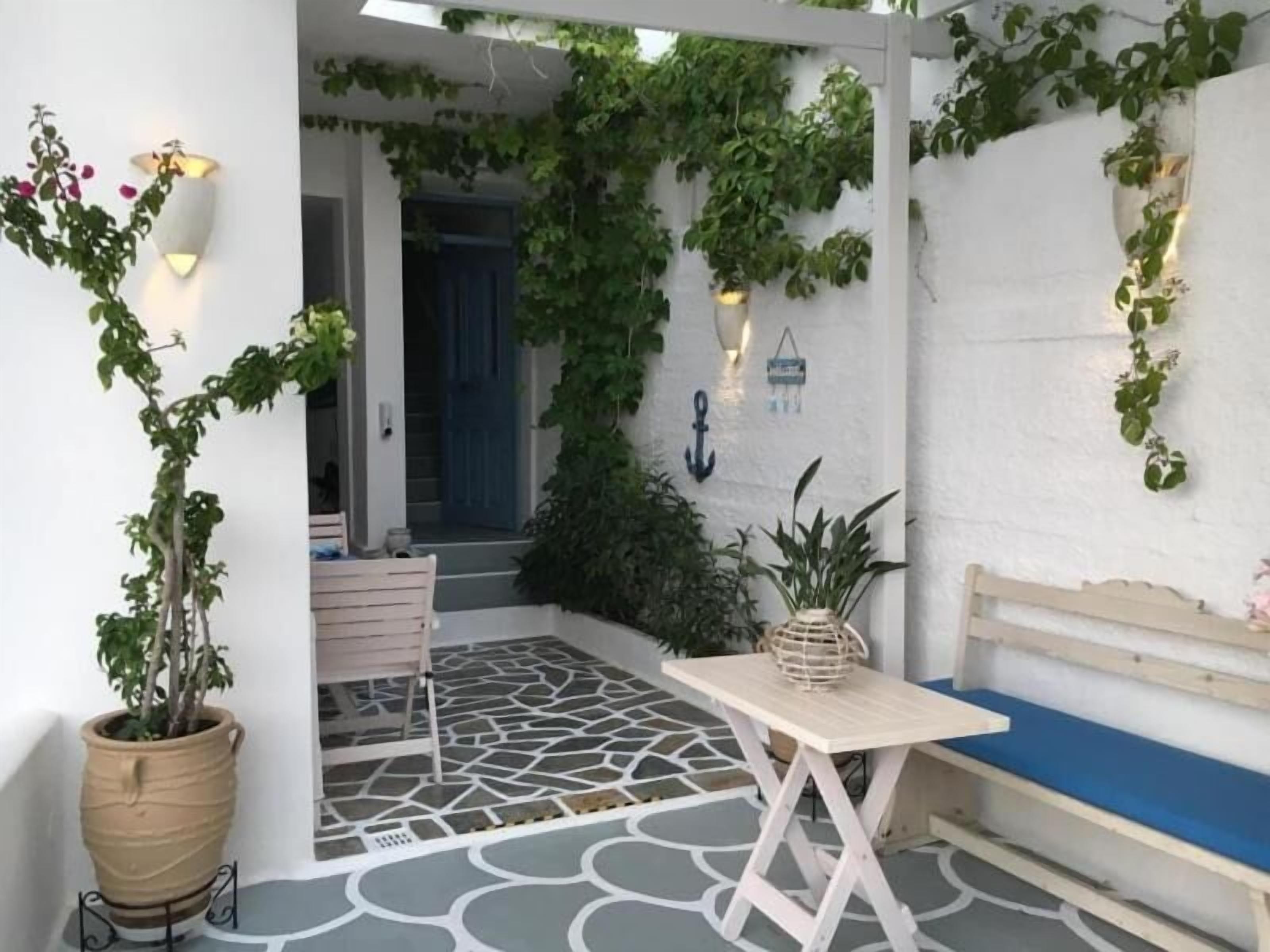 Uma área de estar ao ar livre aconchegante, com piso em padrão de pedra, um banco de madeira e uma mesa.