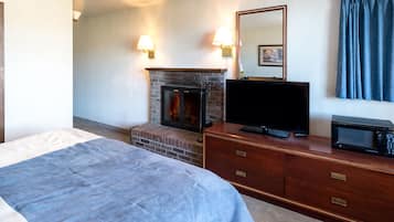 Quarto de hotel com cama, televisão, micro-ondas, lareira e banheiro com chuveiro azul.