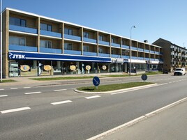 Um hotel com fachada azul, várias varandas e uma placa visível da loja JYSK.