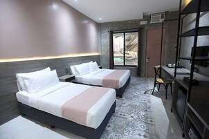 Quarto de hotel com duas camas, uma escrivaninha, uma cadeira e uma televisão.