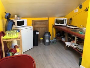 Uma cozinha compacta com geladeira, micro-ondas, pia e diversos utensílios de cozinha.