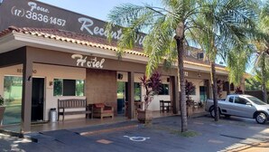 Um hotel com placa, área de estar externa e um carro estacionado.