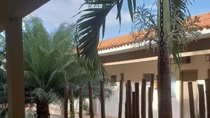 Vista de um edifício com telhado de azulejos e uma fileira de palmeiras na frente.