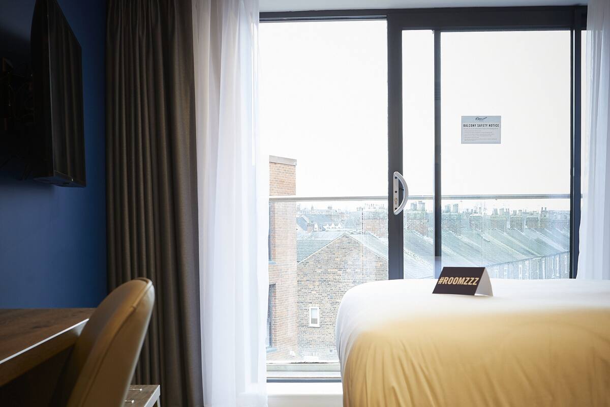 Quarto de hotel com cama, escrivaninha e cadeira.