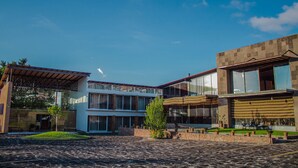 Um edifício moderno com vários andares, grandes janelas e um pátio com plantas em vasos.