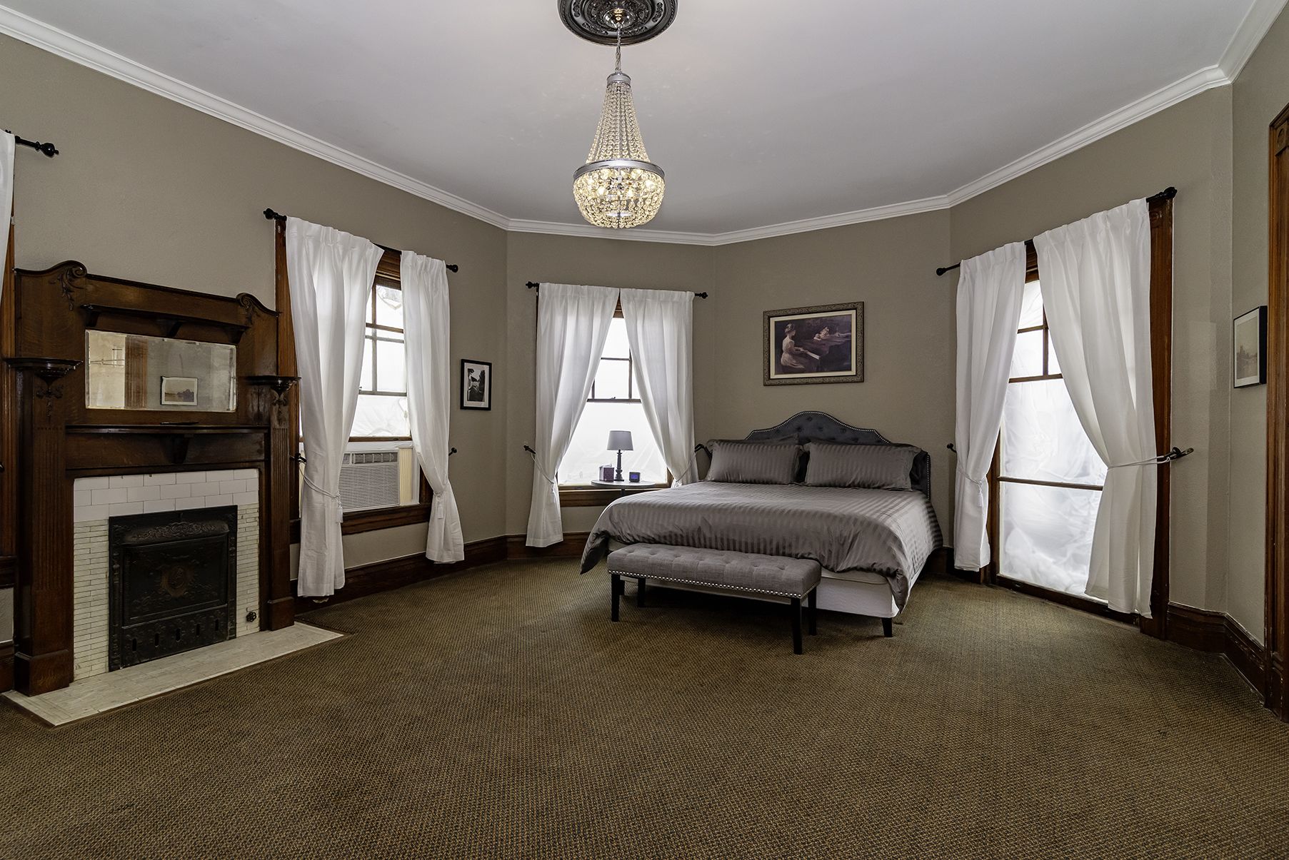 Quarto com uma cama grande, lareira e lustre.