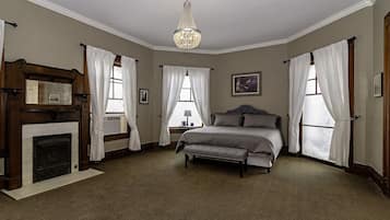 Quarto com uma cama grande, lareira e lustre.