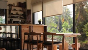 Uma cozinha moderna com móveis de madeira, uma janela grande com vista para folhagem tropical e um aquário embutido.