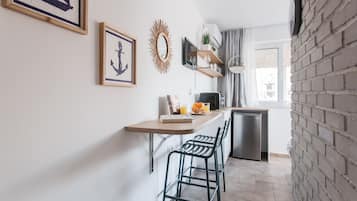 Cozinha moderna com bancada de madeira, dois banquetes altos e uma máquina de lavar louça embutida.