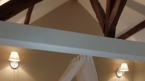 Quarto com cama de dossel, duas luminárias de cabeceira e mesa de cabeceira com um candeeiro.