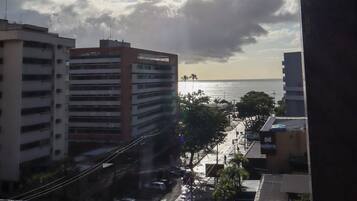 Paisagem urbana com edifícios, rua e um corpo d'água ao longe.