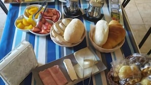 Buffet de café da manhã com diversos alimentos e acompanhamentos sobre uma toalha listrada.