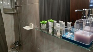 Uma casa de banho moderna com uma prateleira de vidro para produtos de higiene pessoal, zona de duche e um espelho grande.