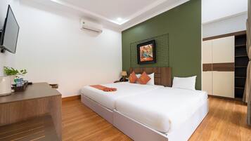 Quarto de hotel com cama, escrivaninha, televisão, ar condicionado, quadro e guarda-roupa.