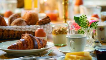 Uma mesa de café da manhã com croissants, uma xícara e um pequeno vaso com uma planta.