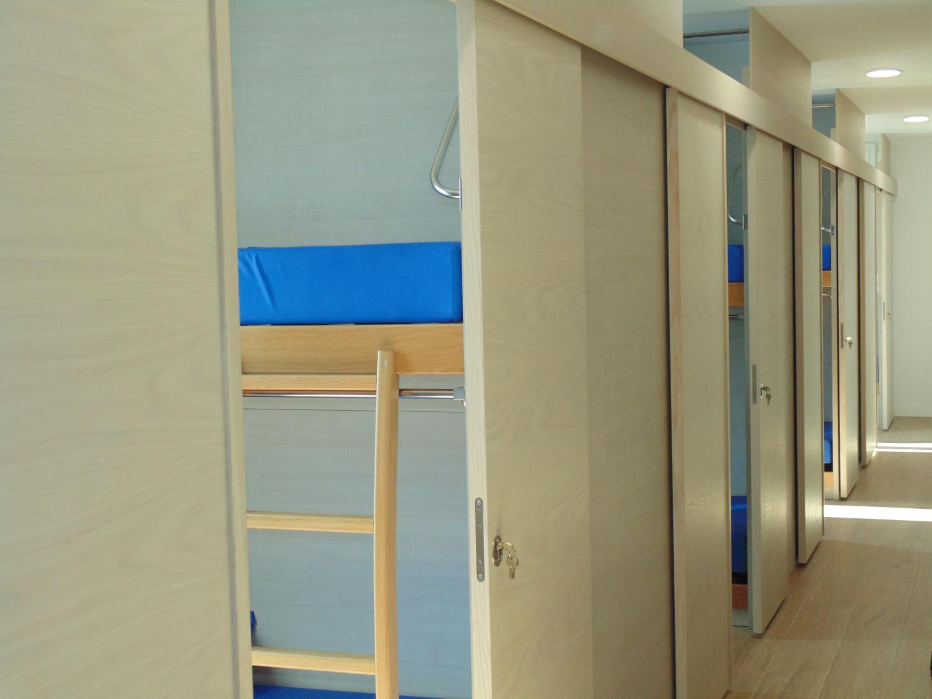 Um quarto com uma cama beliche, uma escada e um guarda-roupa com portas espelhadas.