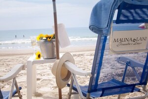 Na praia, areia branca, guarda-sóis, toalhas de praia 