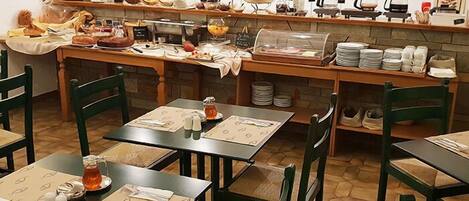 Restaurante com serviço de buffet, incluindo diversas opções de comida e um canto para café.