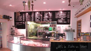 Vitrine com mariscos e peixes em um restaurante, com um quadro negro de menu acima.