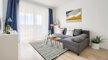 Uma sala de estar moderna com um sofá cinzento, uma mesa de centro e uma planta em vaso.