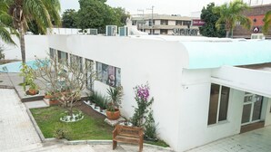 Um edifício com piscina, plantas em vasos e um banco.