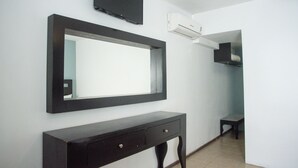 Quarto com um espelho grande, televisão de tela plana e ar condicionado instalado.
