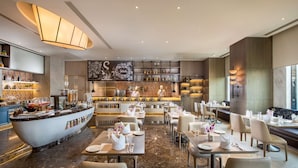Um restaurante moderno com balcão central, mesas para refeições e piso de mármore.