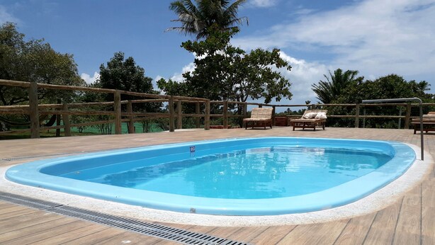 Uma piscina retangular com deck de madeira e guarda-corpo de metal.
