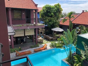 Uma área de piscina com espreguiçadeiras, uma mesa e uma escadaria que dá para um deck coberto.