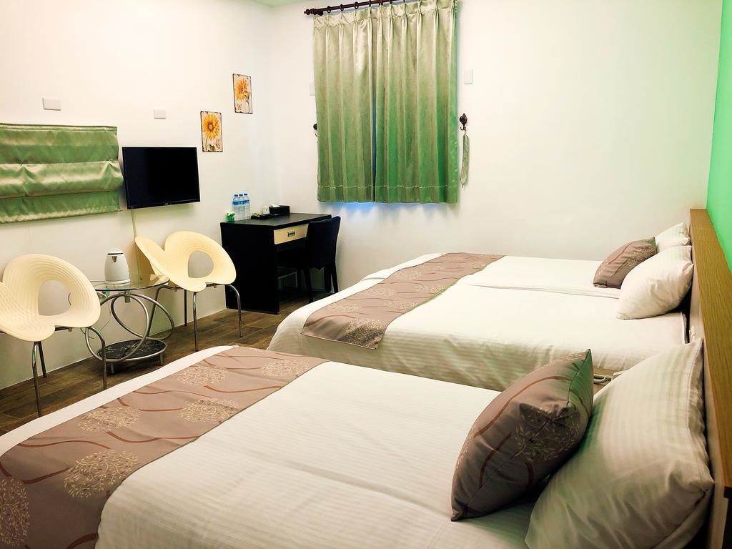 Quarto de hotel com duas camas, uma mesa, uma cadeira, uma televisão e uma cortina.
