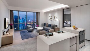 Quarto de hotel moderno com vista para a cidade, área de refeições e cozinha compacta.
