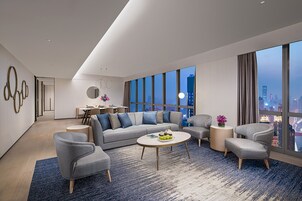 Uma sala de estar moderna com sofá, poltronas, mesa de centro e área de jantar.