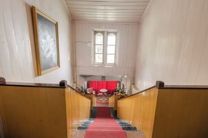 Uma escadaria com um tapete vermelho que leva a um quarto com cortina vermelha e uma janela.