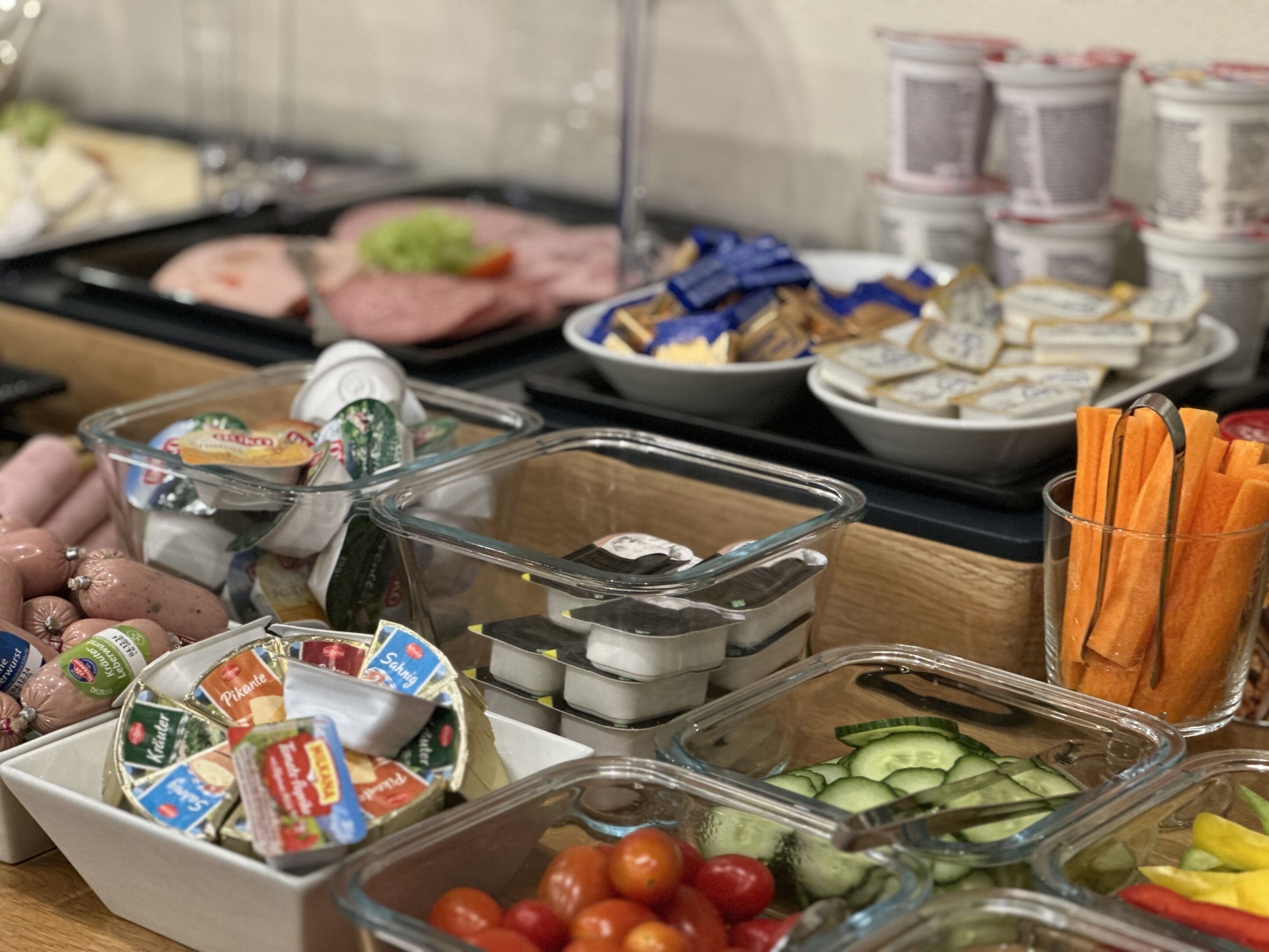 Buffet com diversos alimentos, incluindo carnes, queijos e vegetais.