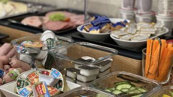 Buffet com diversos alimentos, incluindo carnes, queijos e vegetais.