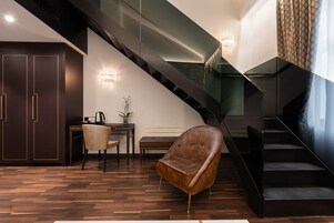 Interior moderno com escada, piso de madeira, uma poltrona marrom, uma mesa de jantar com cadeiras e um armário.