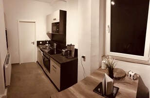 Cozinha compacta com fogão, micro-ondas e cafeteira. Há uma janela com vista para o exterior.